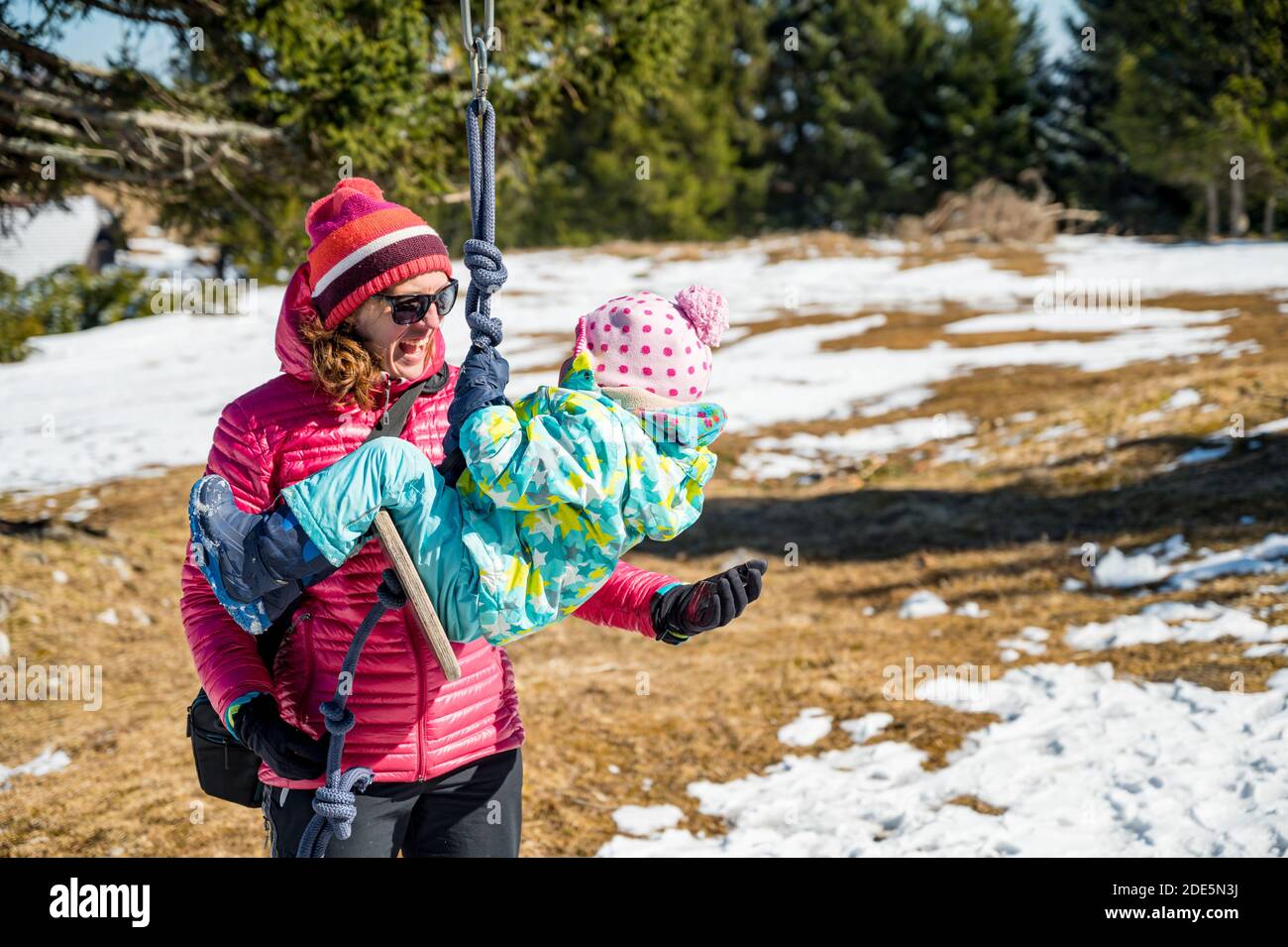 Happy mother protecting her daughter while she swings outdoor Stock ...