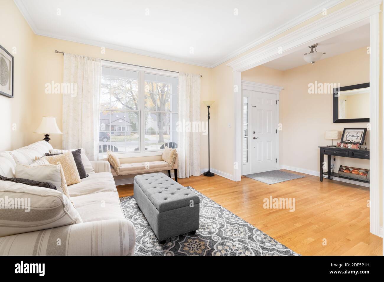 A bright, cozy living room with a couch and ottoman looking towards a ...