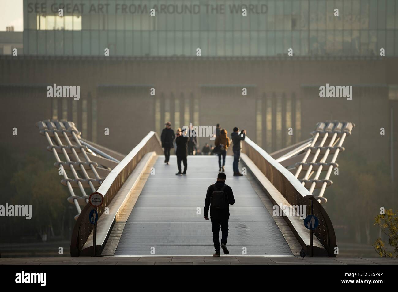 People walking over Millennium Bridge at sunset, with Tate Modern ...