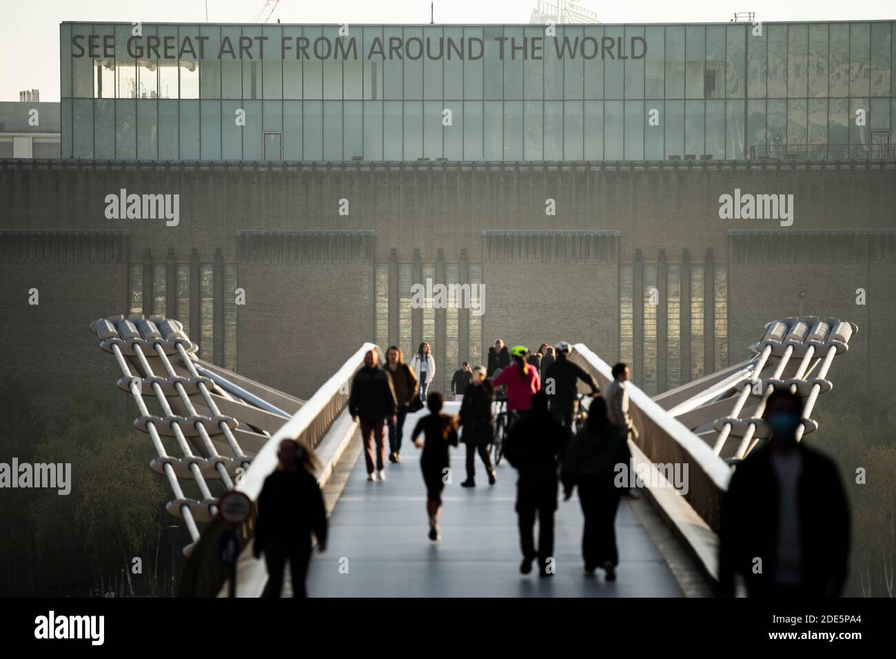 People walking over Millennium Bridge at sunset, with Tate Modern ...