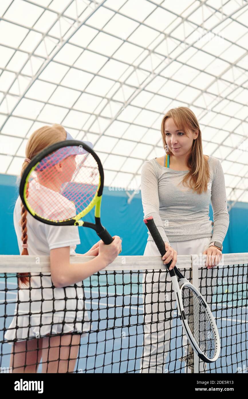 Young female tennis trainer in activewear and cute girl with tennis ...