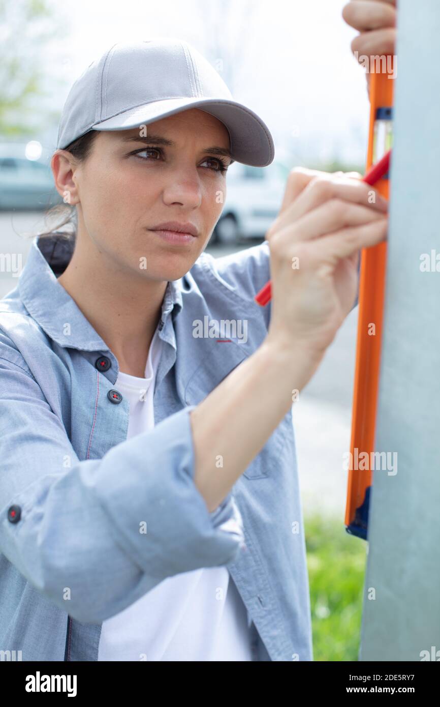 female contractor using spirit level on vertical post Stock Photo - Alamy