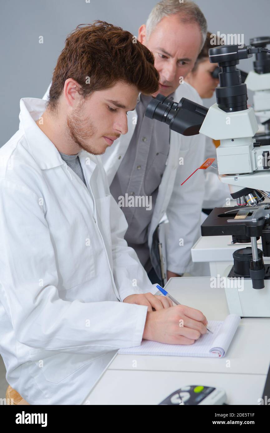 male biology teacher looking through microscope in classroom Stock ...