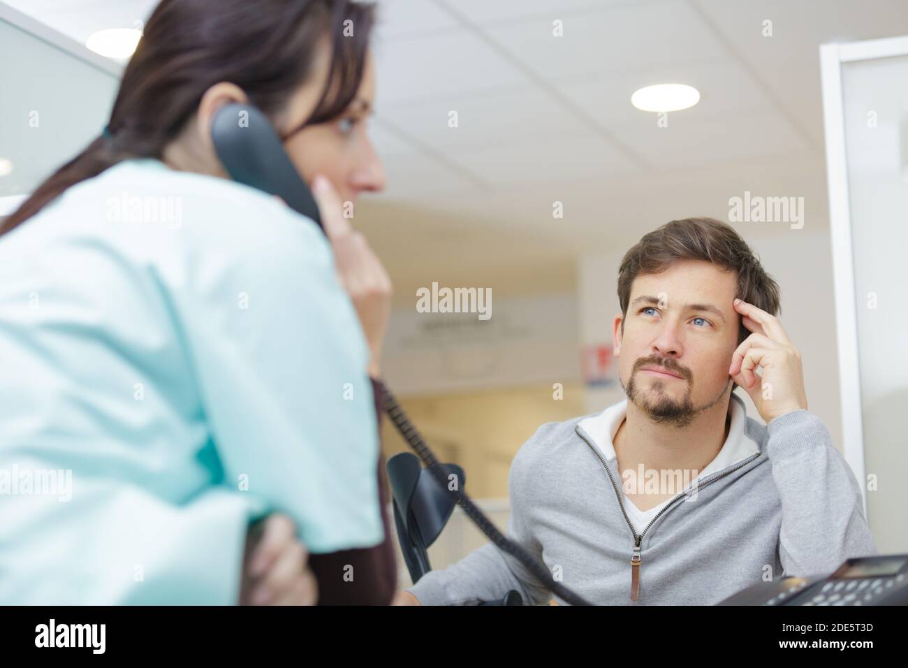male patient looking at female receptionist using landline phone Stock ...