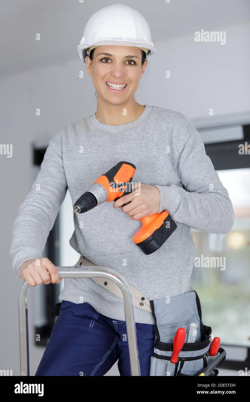 female contractor on stepladder holding cordless power-tool Stock Photo ...