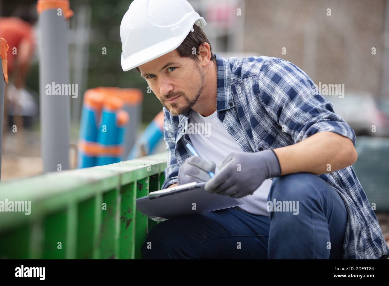 workman checking site and making notes on clipboard Stock Photo - Alamy