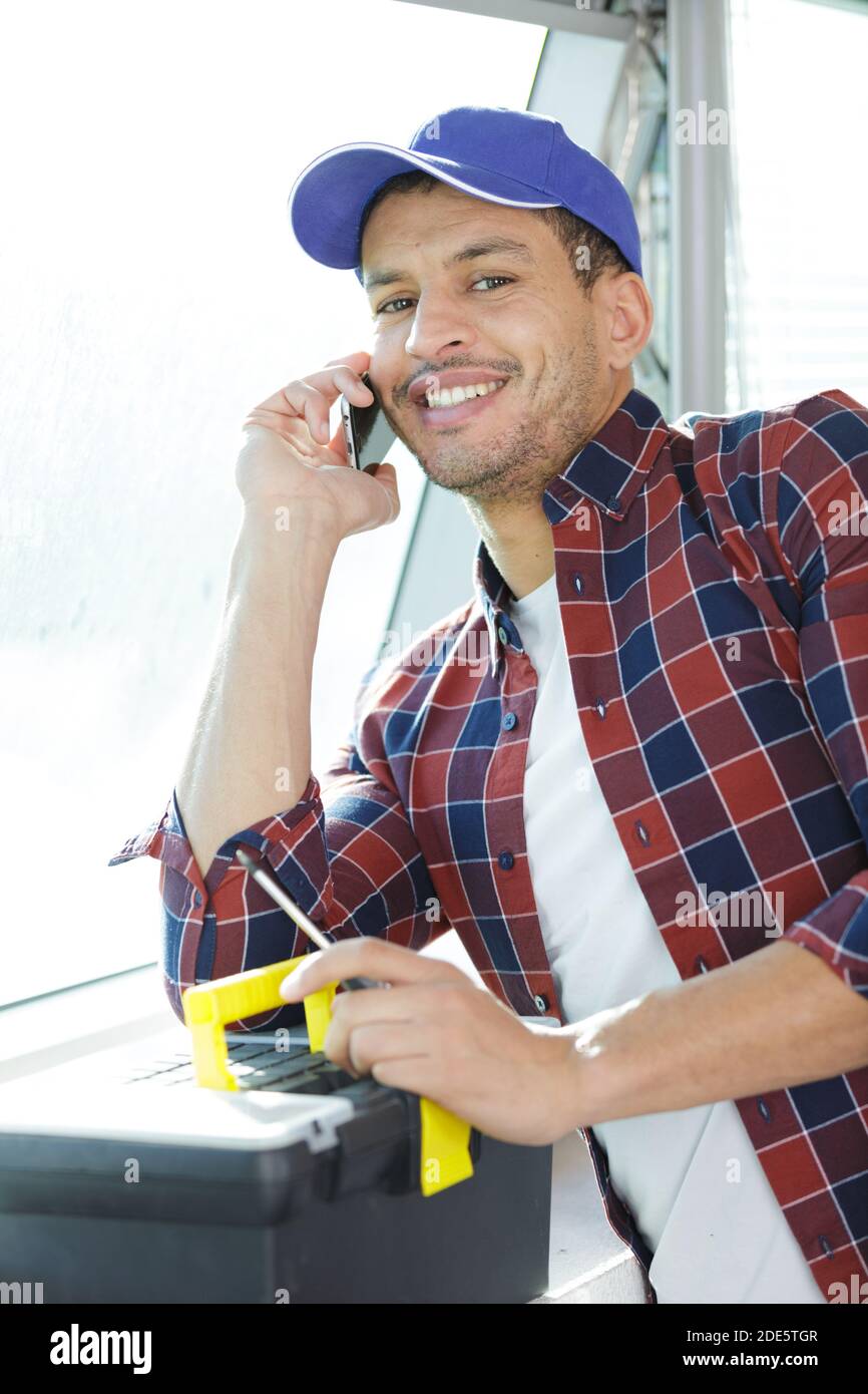 handyman with toolbox talks on the telephone Stock Photo - Alamy