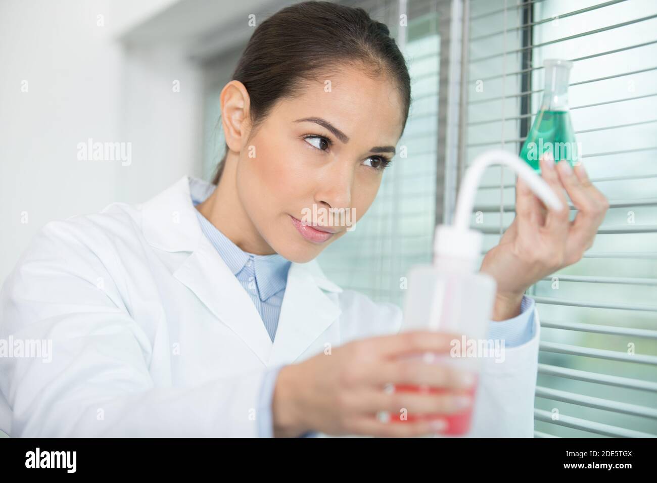 female scientist holding dropper and glass flask Stock Photo - Alamy