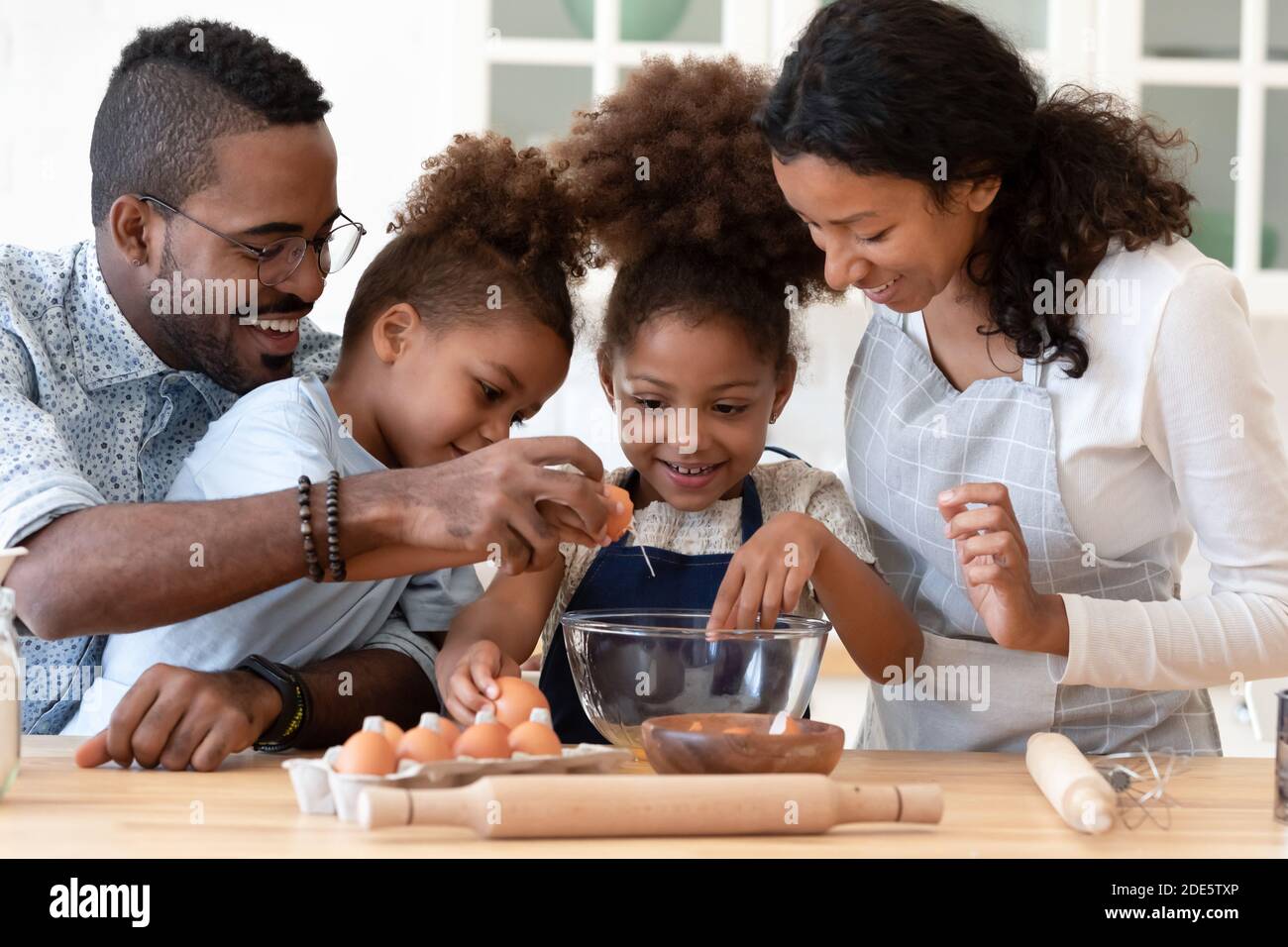 Loving friendly afro american family mixing dough for homemade pastries ...