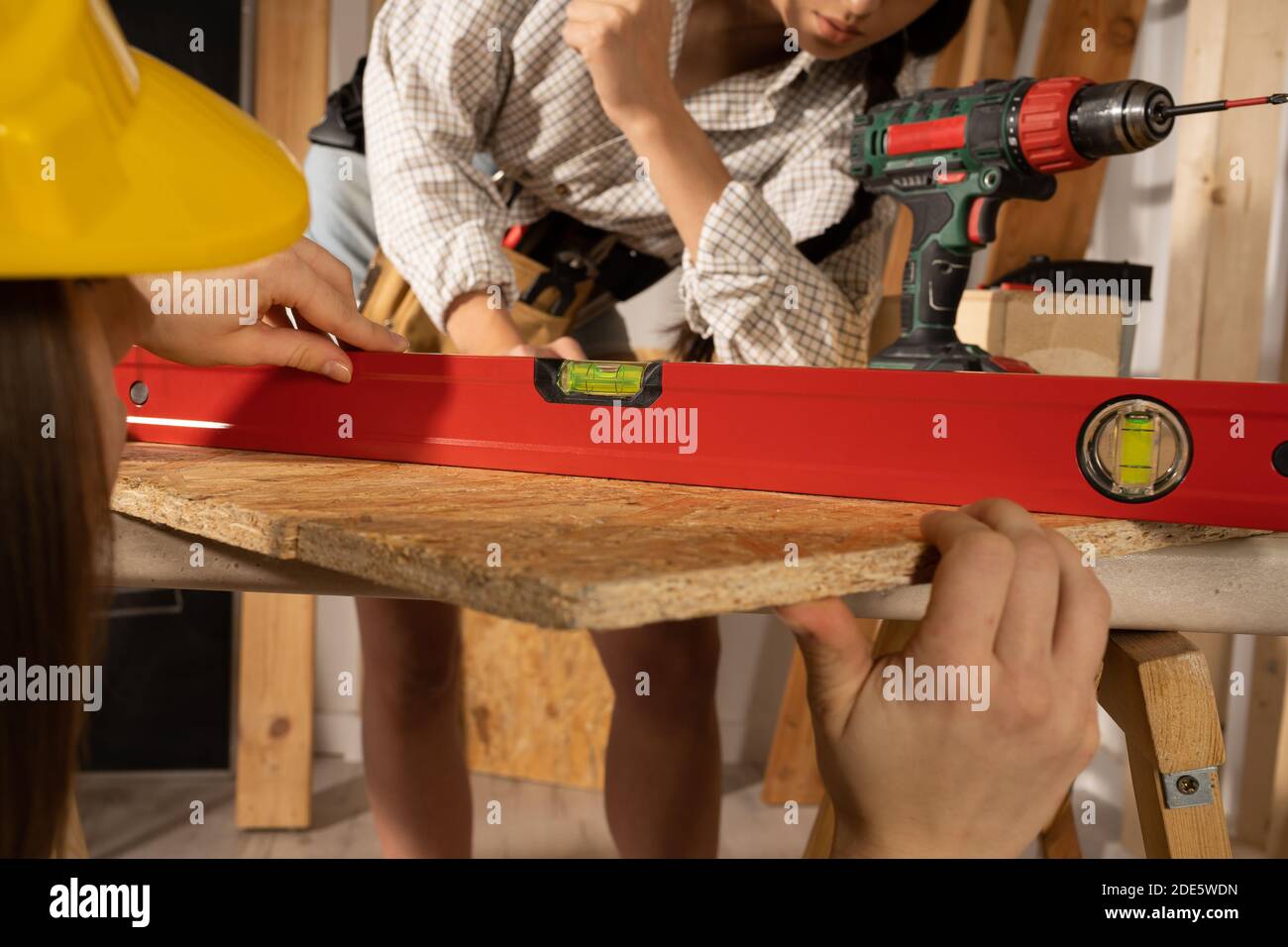 The blonde puts a red spirit level to the table top and the brunette ...
