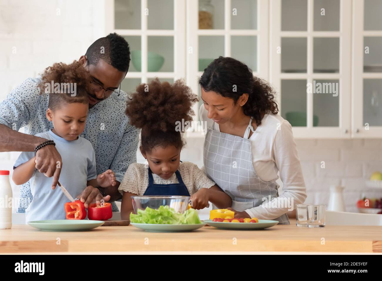 African mother and father teaching children cook meals at kitchen Stock ...