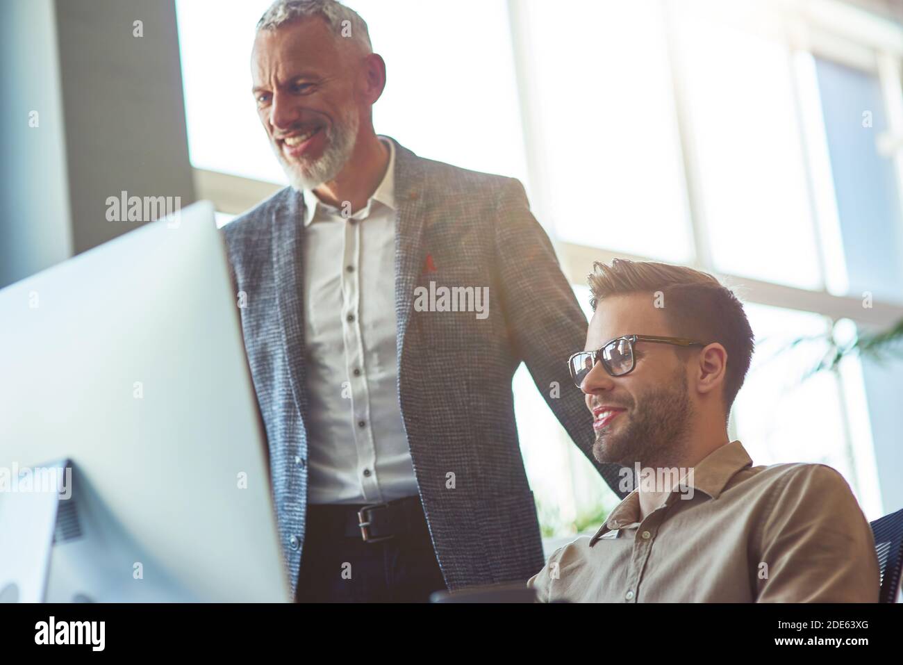 Cheerful mature businessman, male boss explaining something to young ...