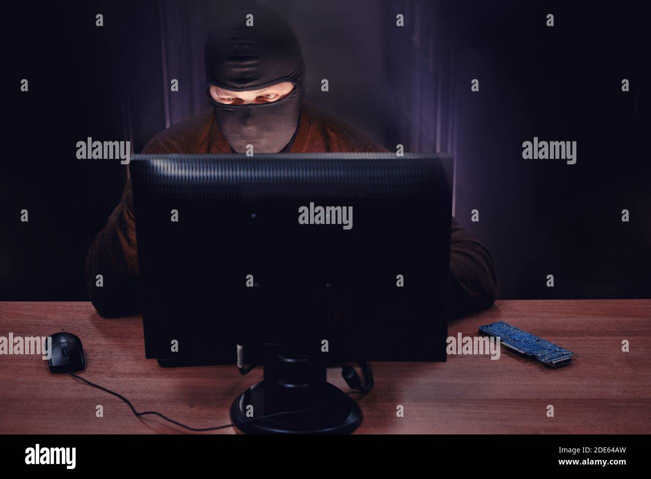 Hacker in balaclava steals information in the server room. Concept of ...
