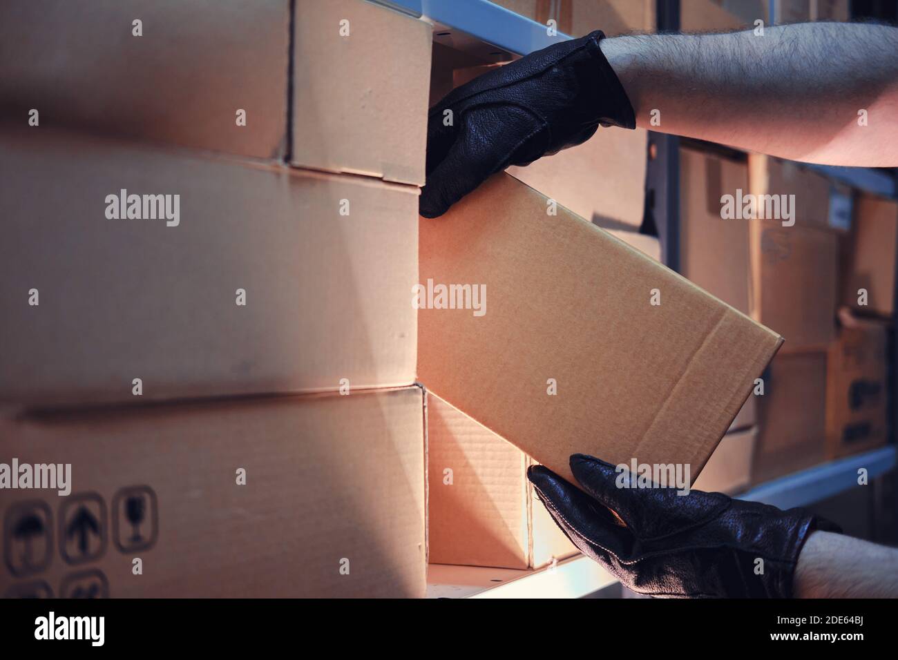 Hands of a man in leather gloves take a box of goods in a warehouse at ...