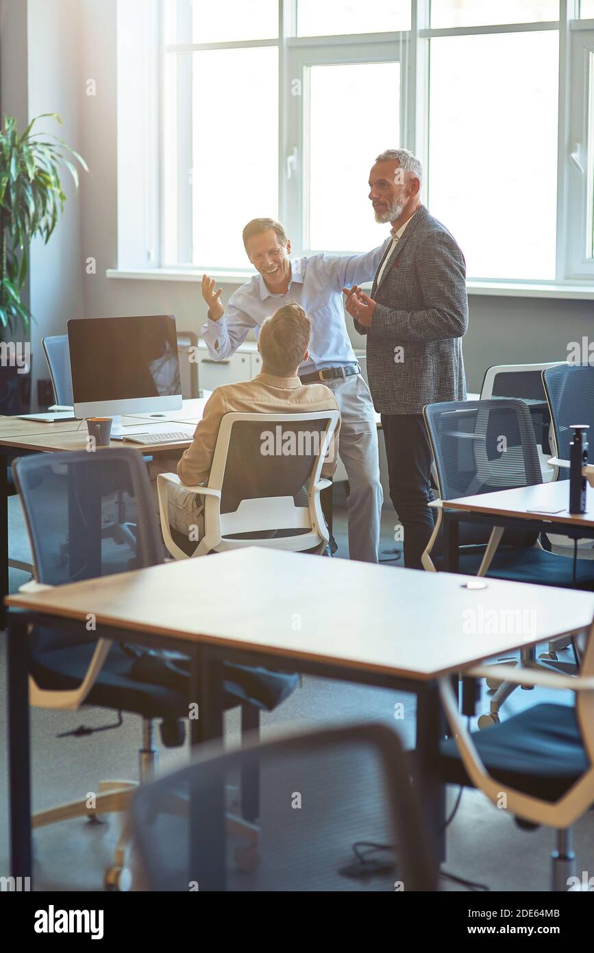 Group of happy coworkers talking, discussing something and smiling ...