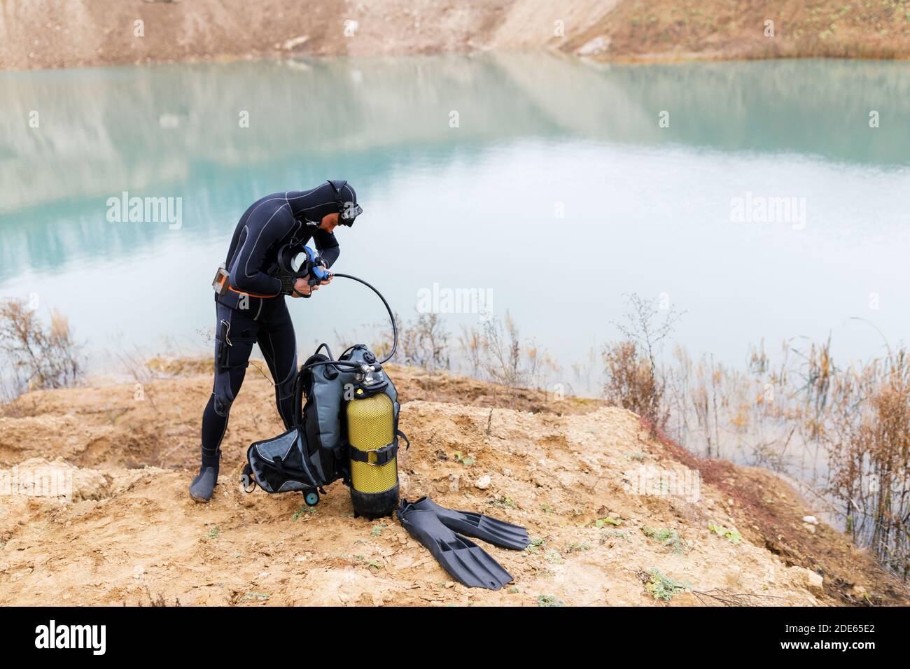 A lifeguard in a wetsuit is preparing to dive into the pond Stock Photo ...