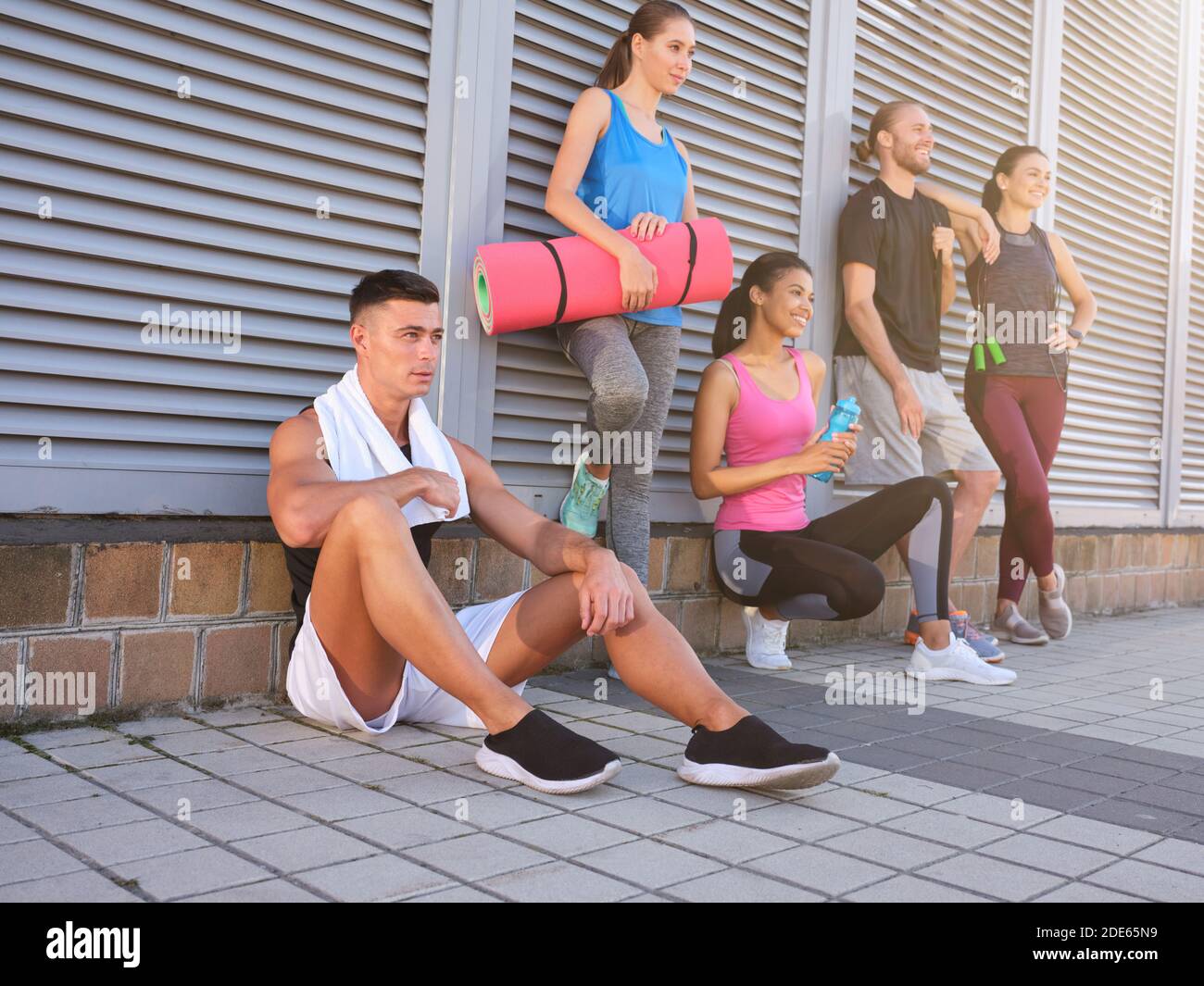 Young multiracial people resting near wall on street Stock Photo - Alamy