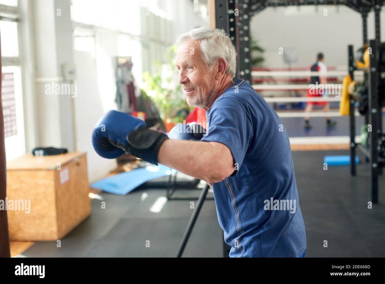 Senior man beats punching bag in gym Stock Photo - Alamy