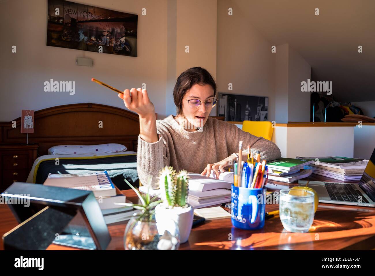 Young female student focused on her desk in the bedroom, studying at ...