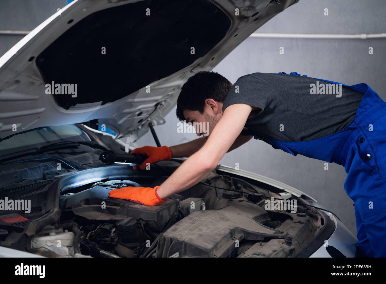 A worker uses a lamp to illuminate a automobile engine Stock Photo - Alamy