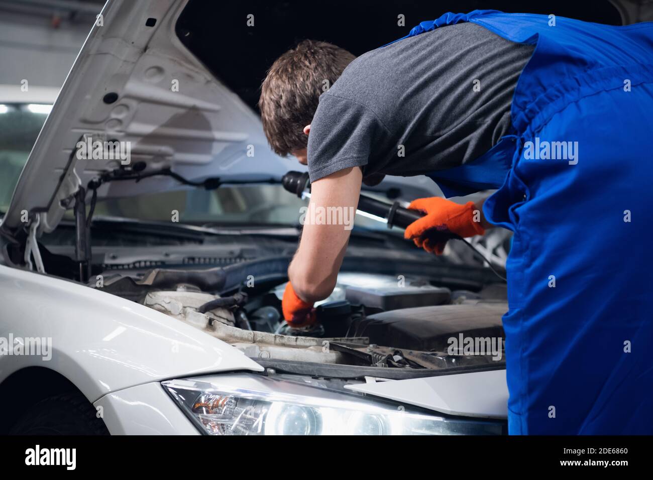 A mechanic uses a lamp to illuminate a car engine Stock Photo - Alamy