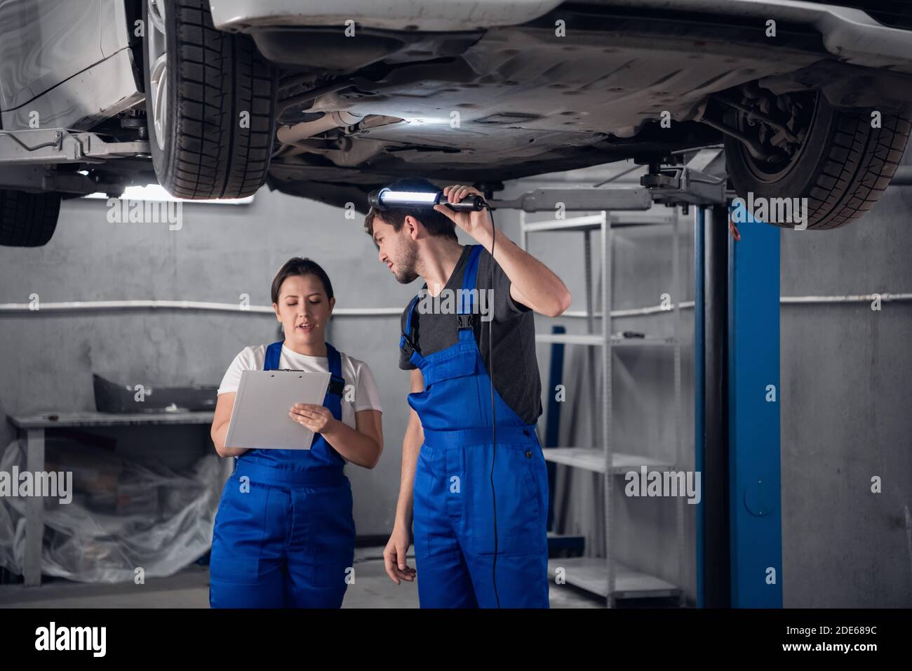 Mechanic and assistant inspect the bottom of the automobile Stock Photo ...
