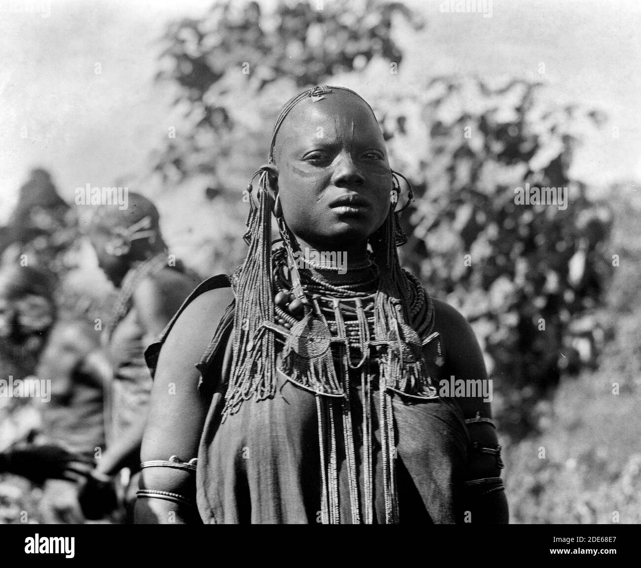 Original Caption: Tanganyika. Arusha. Woman of Tanganyika weighted down ...