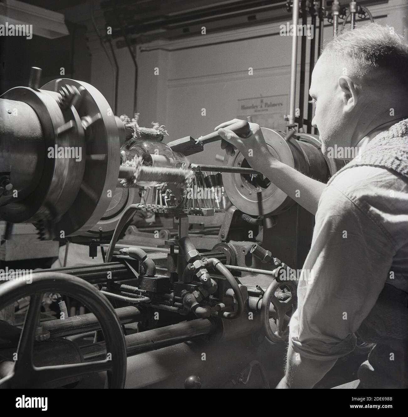 1950s, historical, an industrial worker sitting at a mechanical lathe ...
