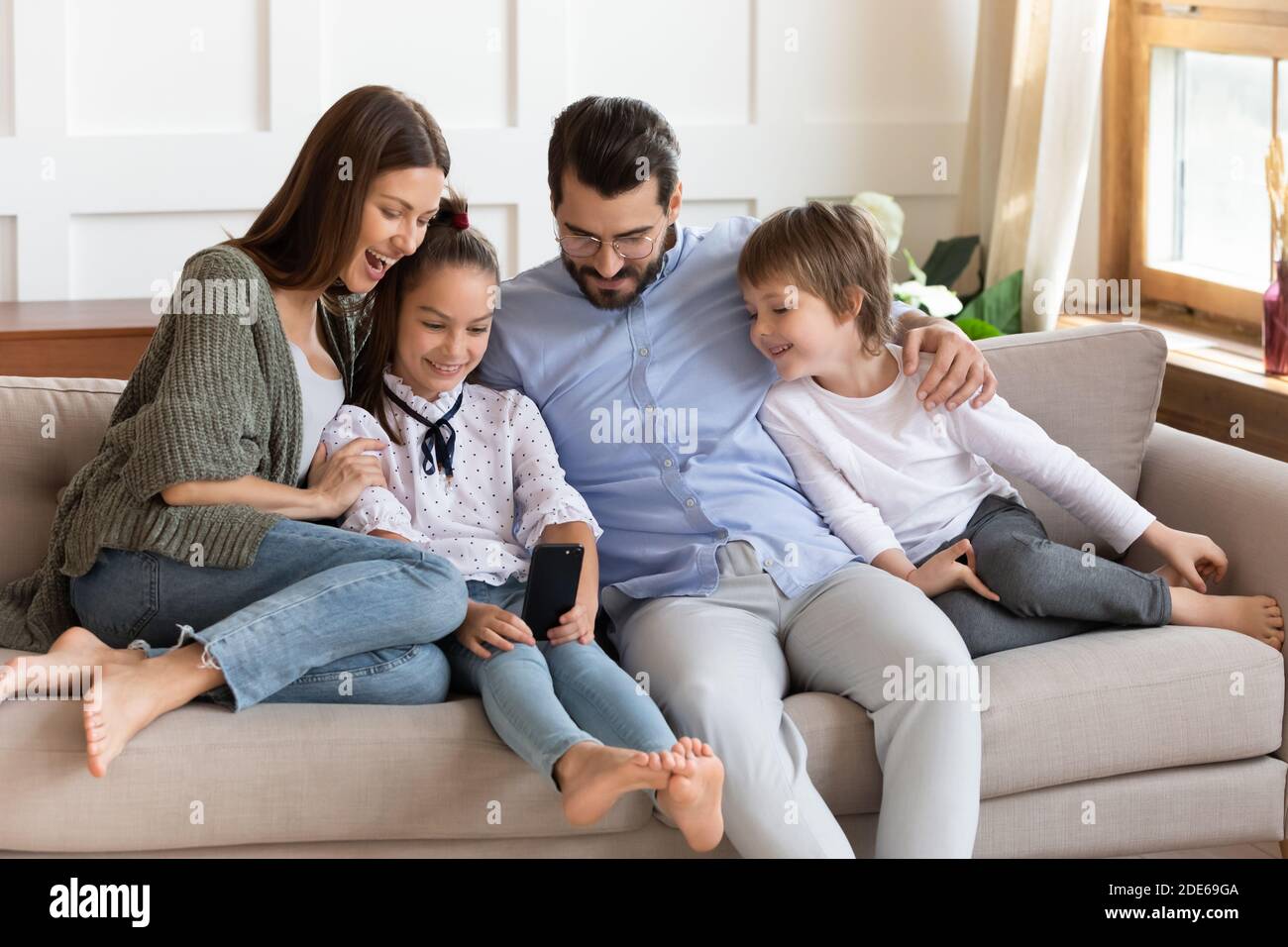 Happy family with kids watch video on cell at home Stock Photo - Alamy