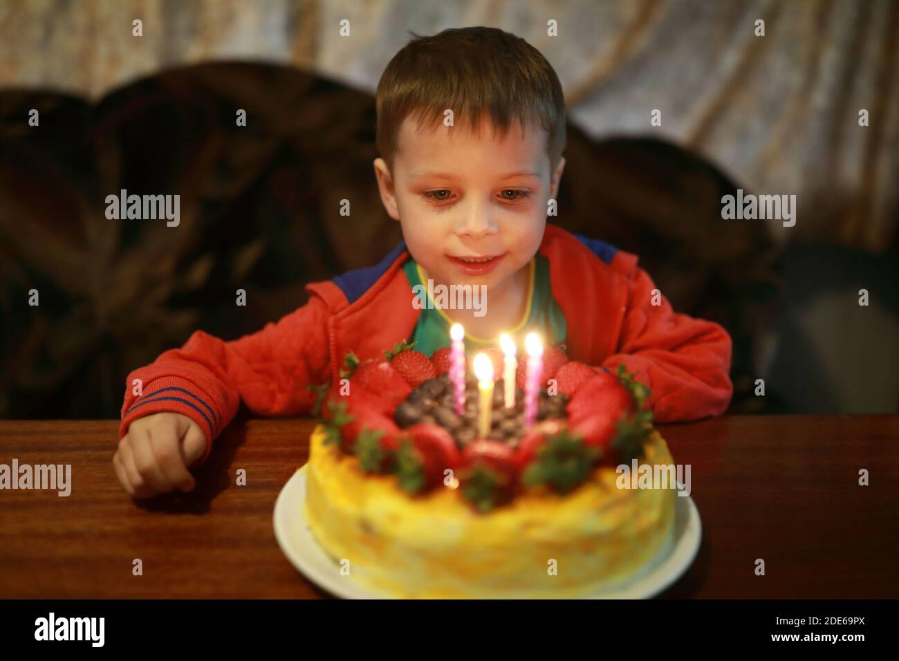 Child blows out candles on birthday cake Stock Photo - Alamy