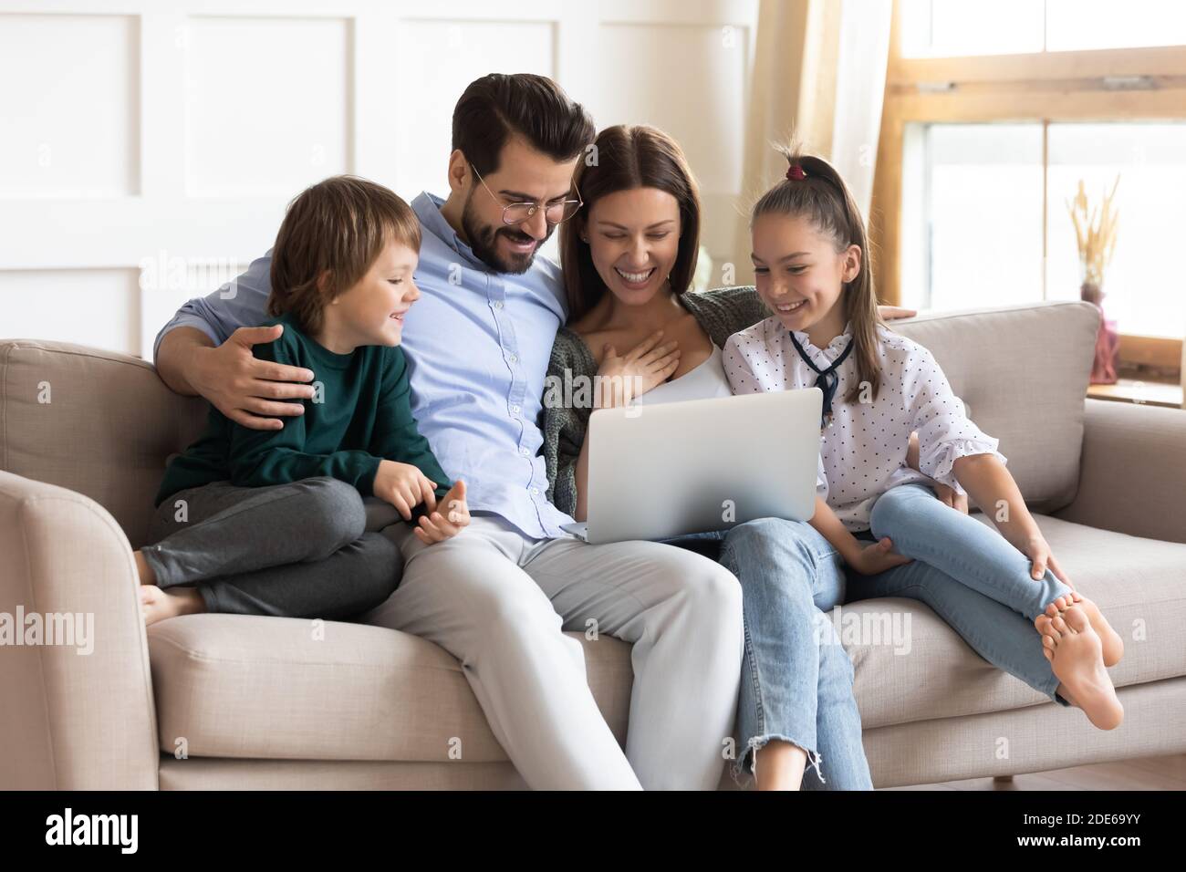 Overjoyed family with children relax at home with laptop Stock Photo ...