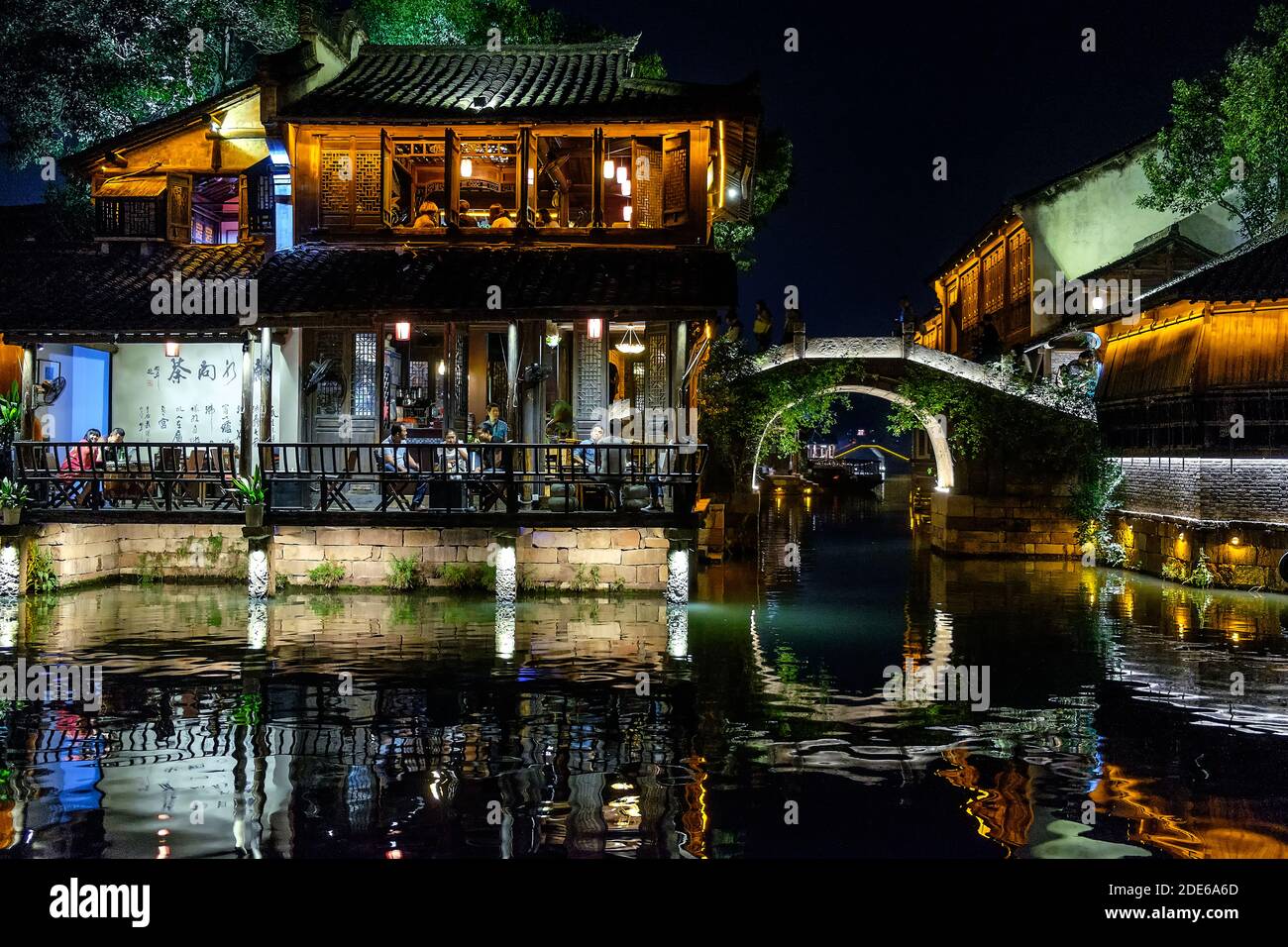 Night time view of people eating and socialising in a waterfront ...
