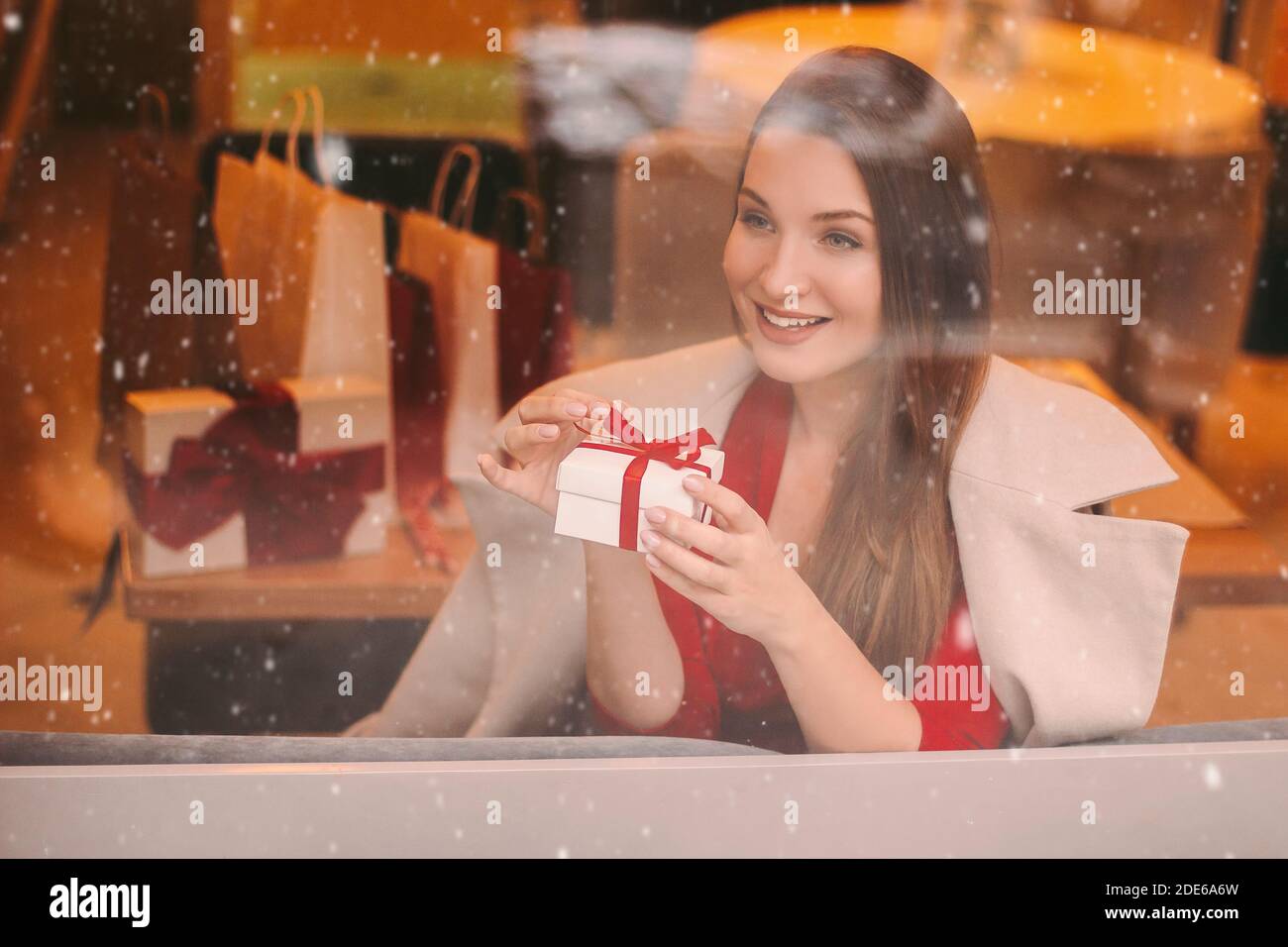 Portrait happy young beautiful woman open gift box, look in window and ...