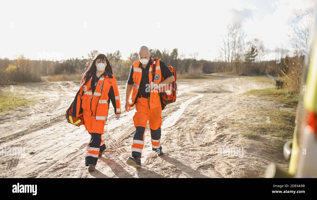 Two paramedics in full equipment walking towards ambulance vehicle ...