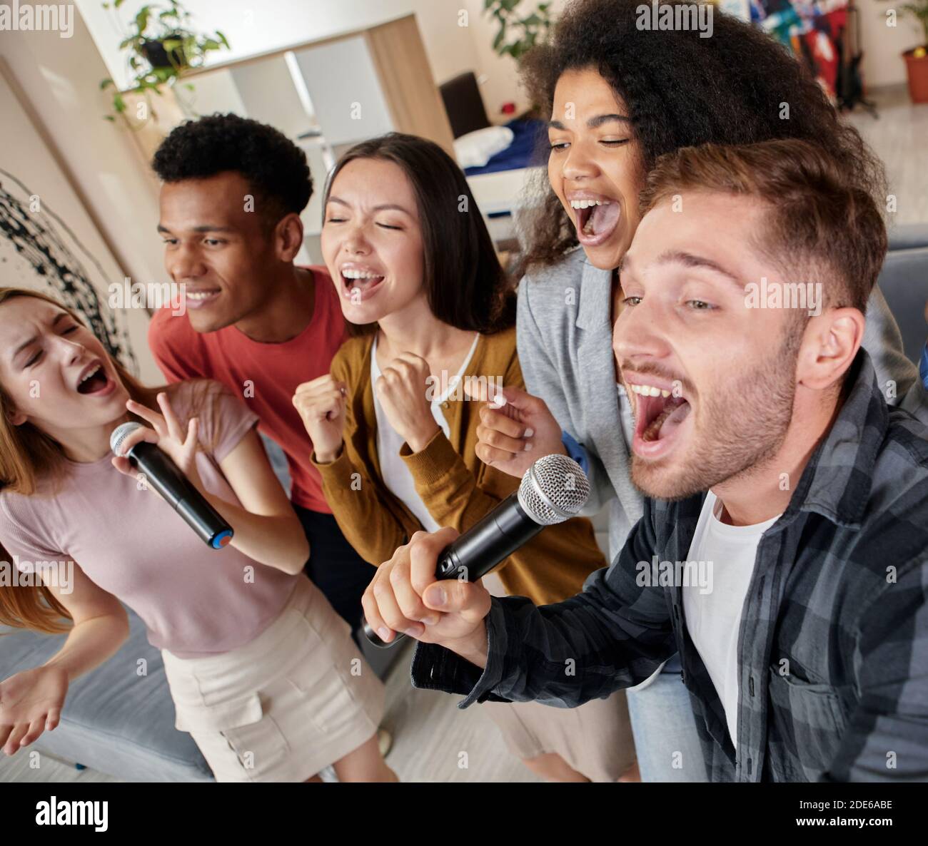Face the song. Enthusiastic multicultured friends singing with ...
