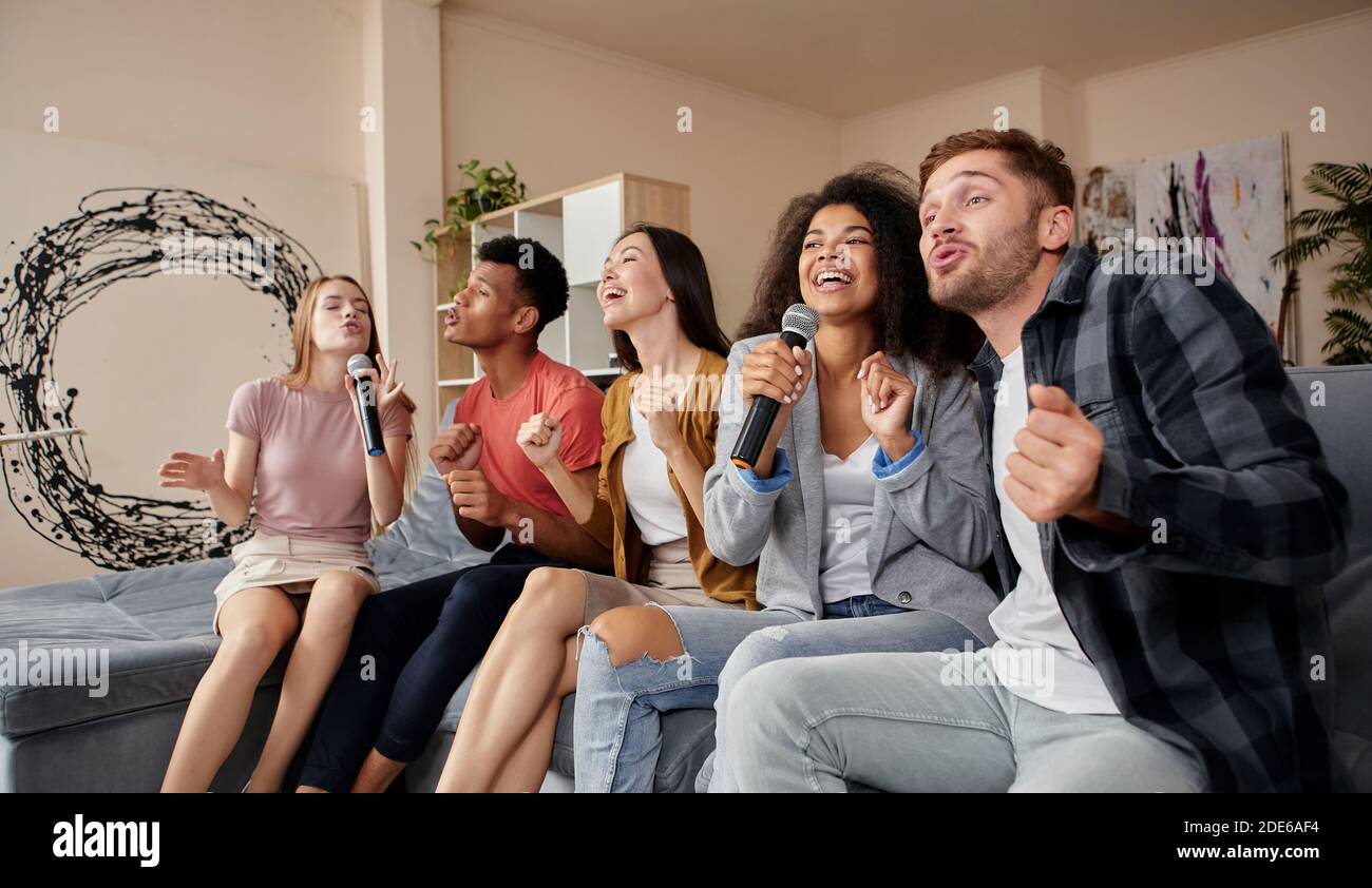 Just sing. Joyful multicultured friends looking enthusiastic while ...