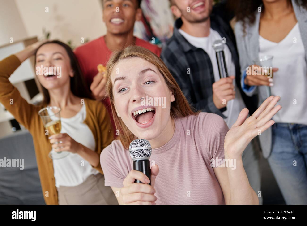 Sharing Joy. Beautiful young girl holding microphone and singing while ...