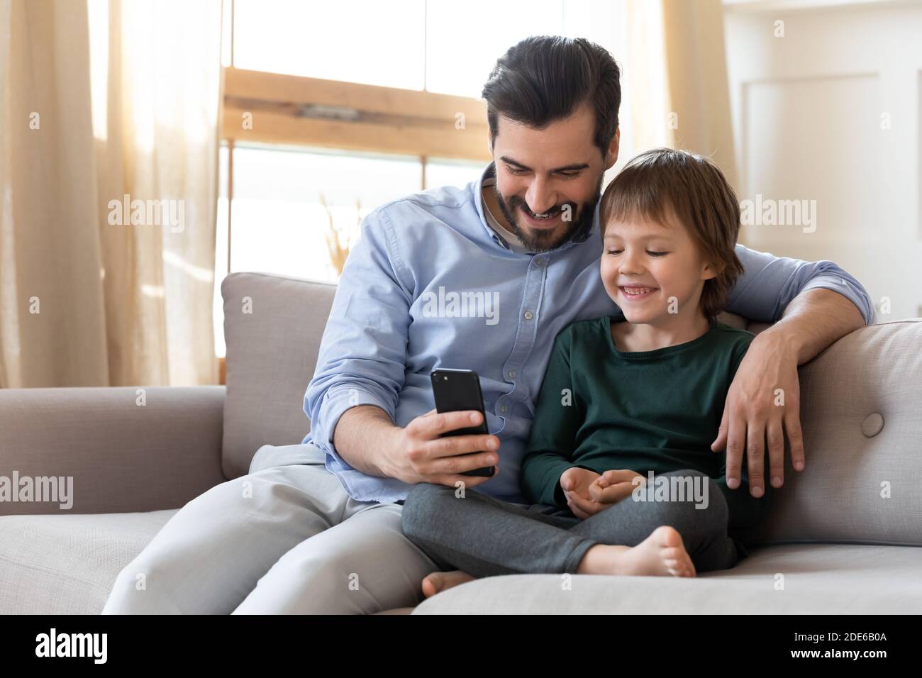 Happy dad and little son relax at home using cellphone Stock Photo - Alamy