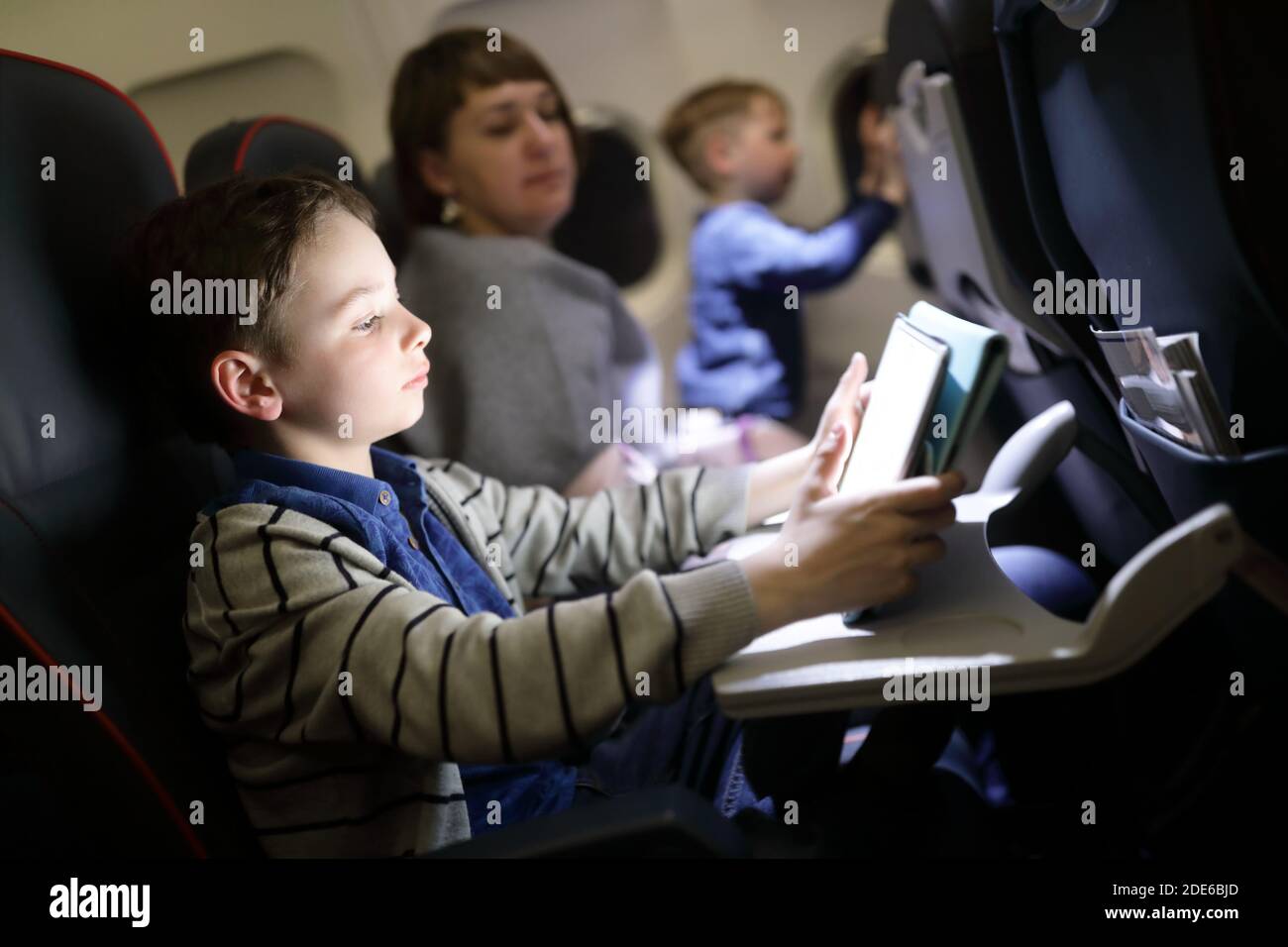 Child using tablet in plane at night Stock Photo - Alamy