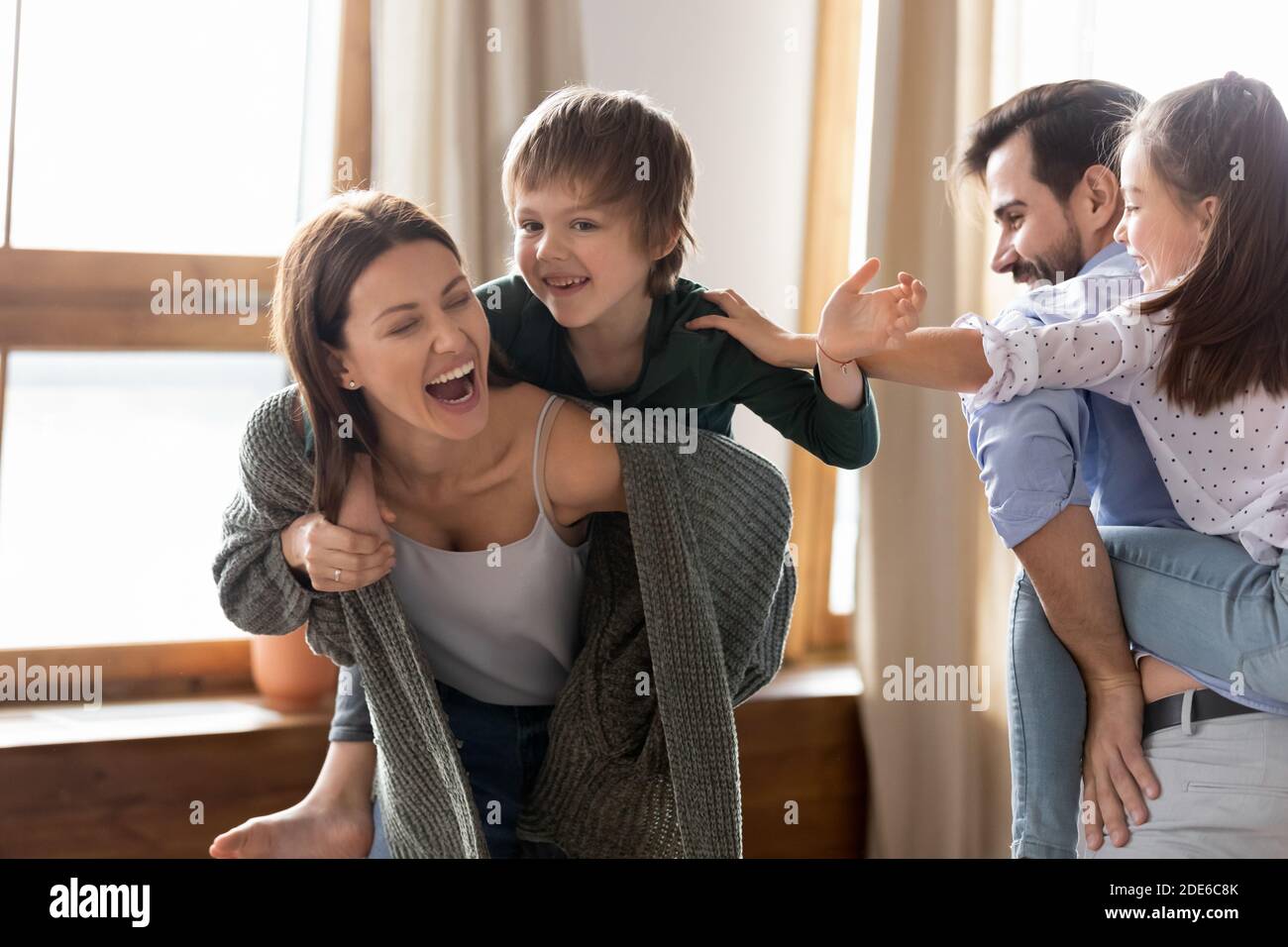 Overjoyed parents have fun playing with children Stock Photo - Alamy