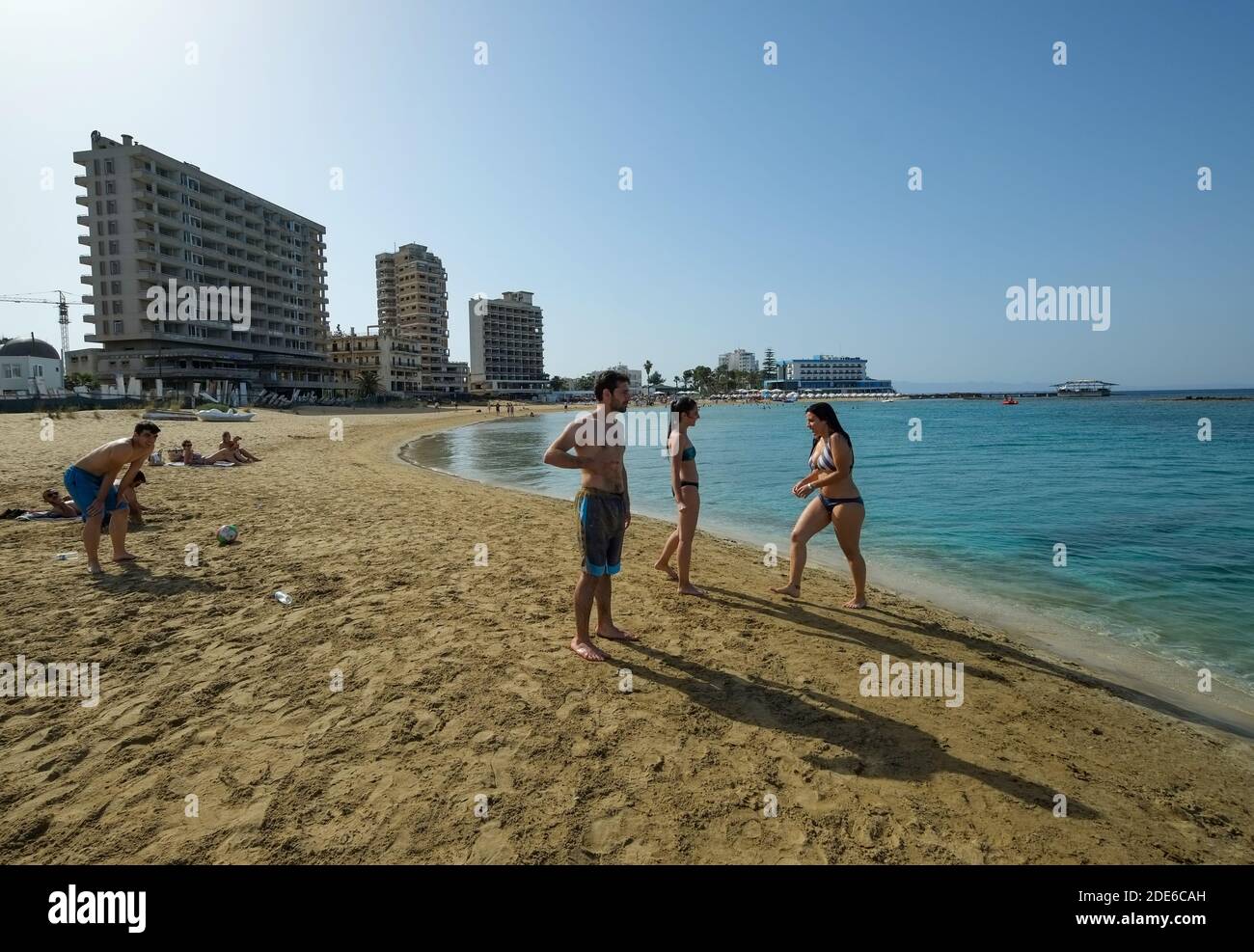 Varosha, Cyprus. Tourists play on the beach in front of abandoned ...