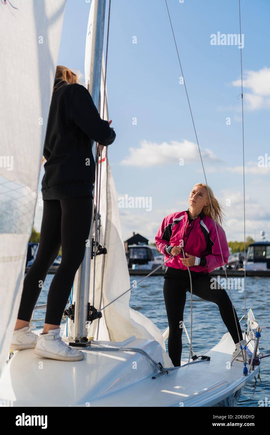 Cute blondes on the pier prepare a sailing yacht for a regatta, pull ...