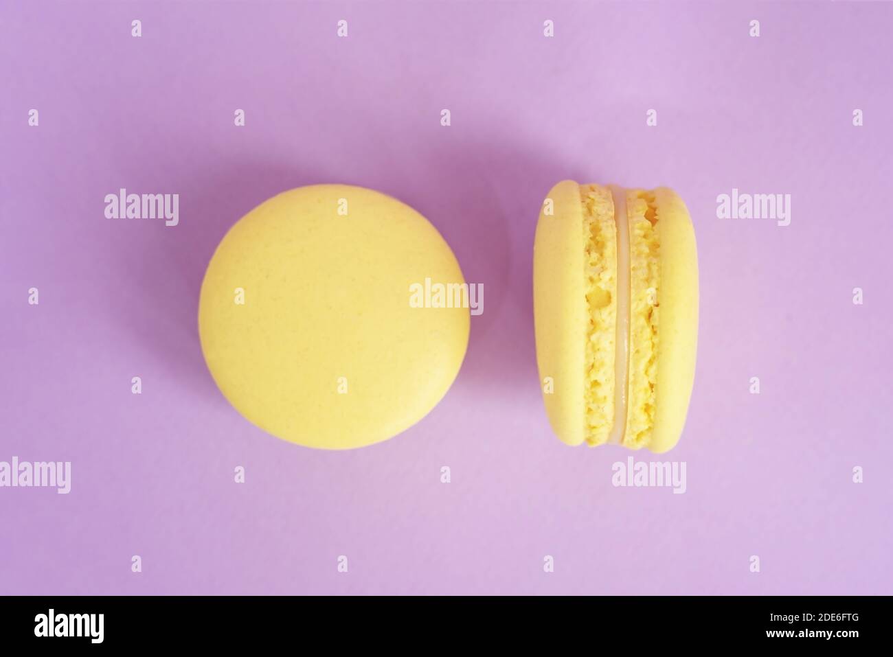 Two tasty french yellow colored macarons on the purple background ...