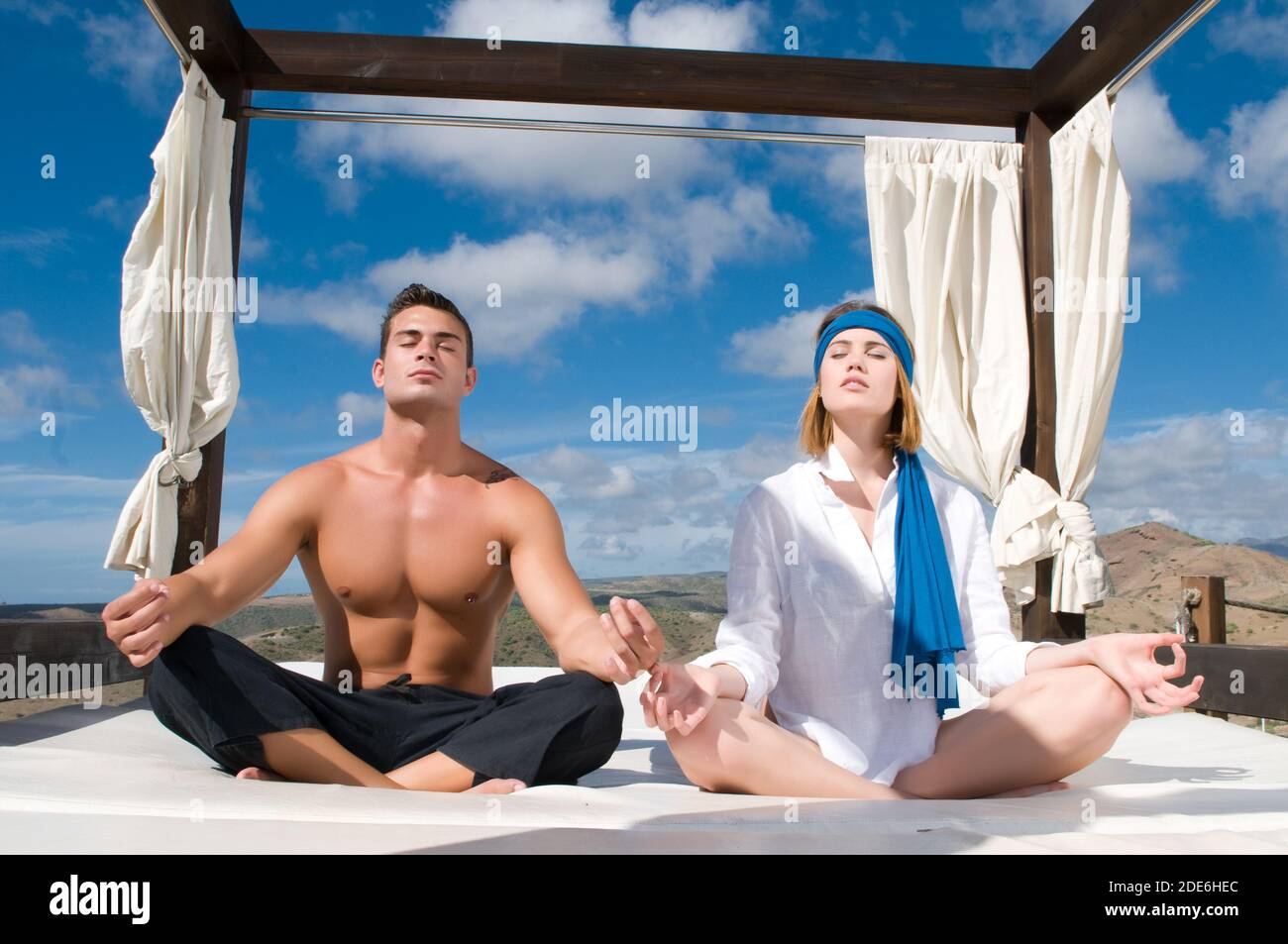 young couple meditating on chill out bed under blue summer sky Stock ...