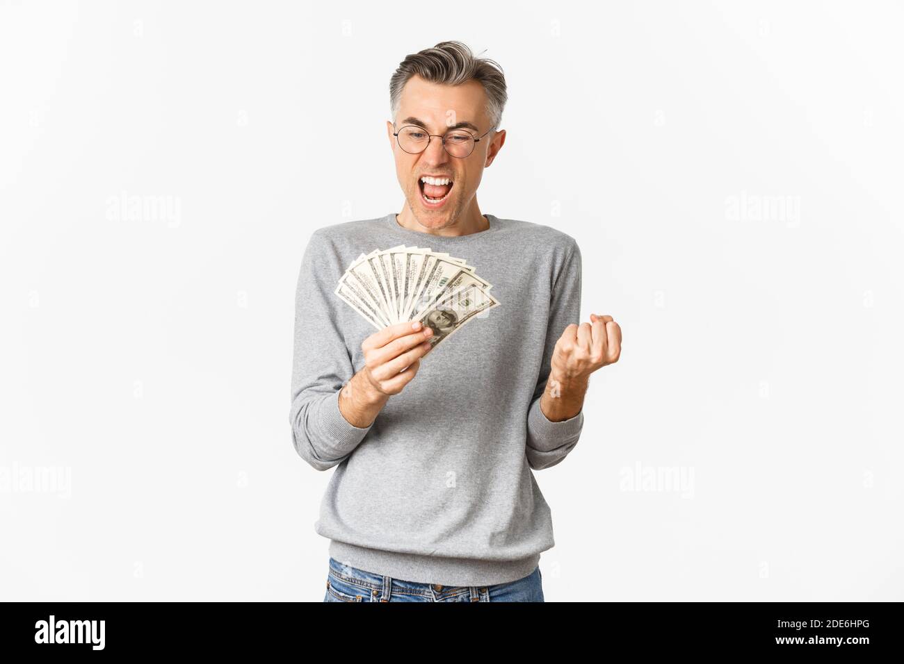 Image of cheerful middle-aged man in glasses and gray sweater, winning ...