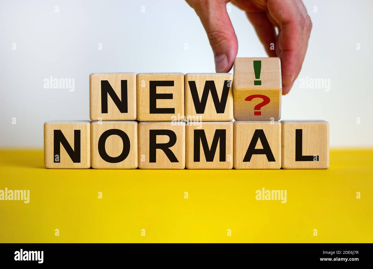 Time to new normal. Male hand turns a cube with question mark and ...