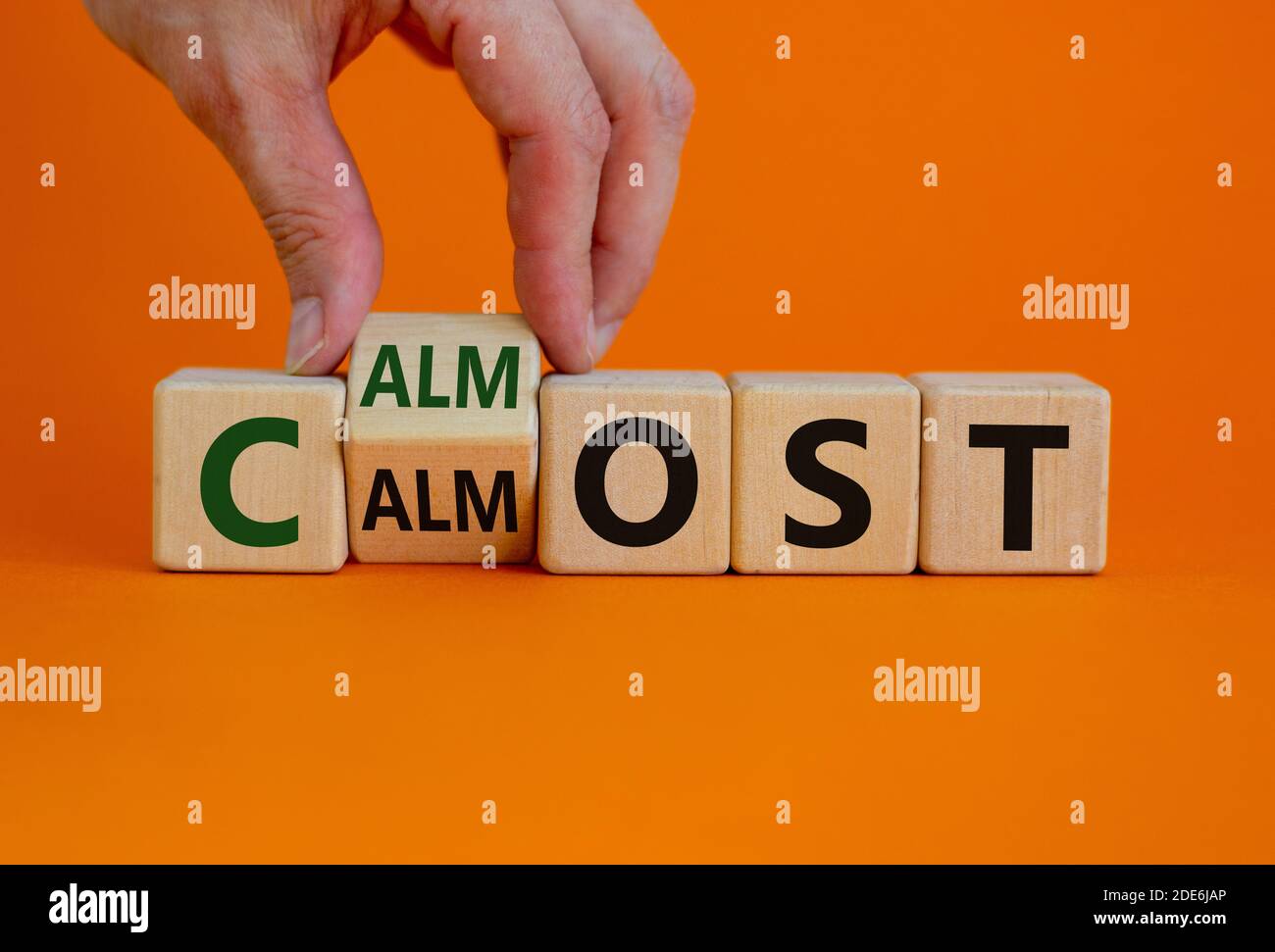 Calm almost. Male hand turns a wooden cube with words 'calm almost ...