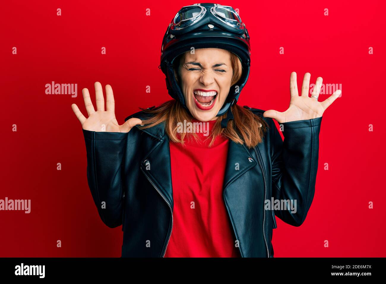 Hispanic young woman wearing motorcycle helmet celebrating mad and ...