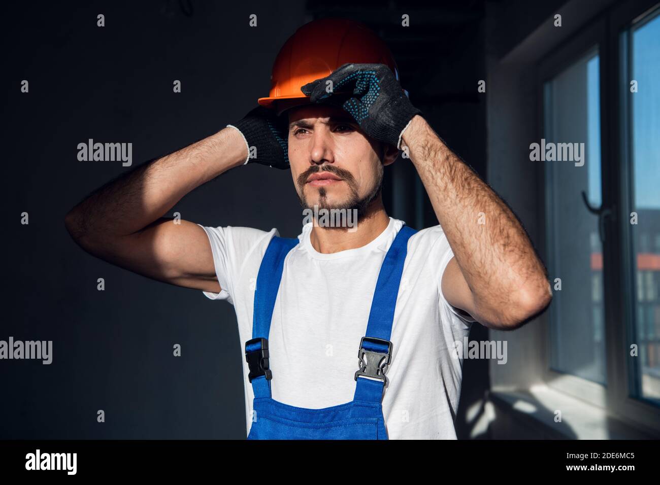 A repairman in black gloves and a blue uniform puts a construction ...