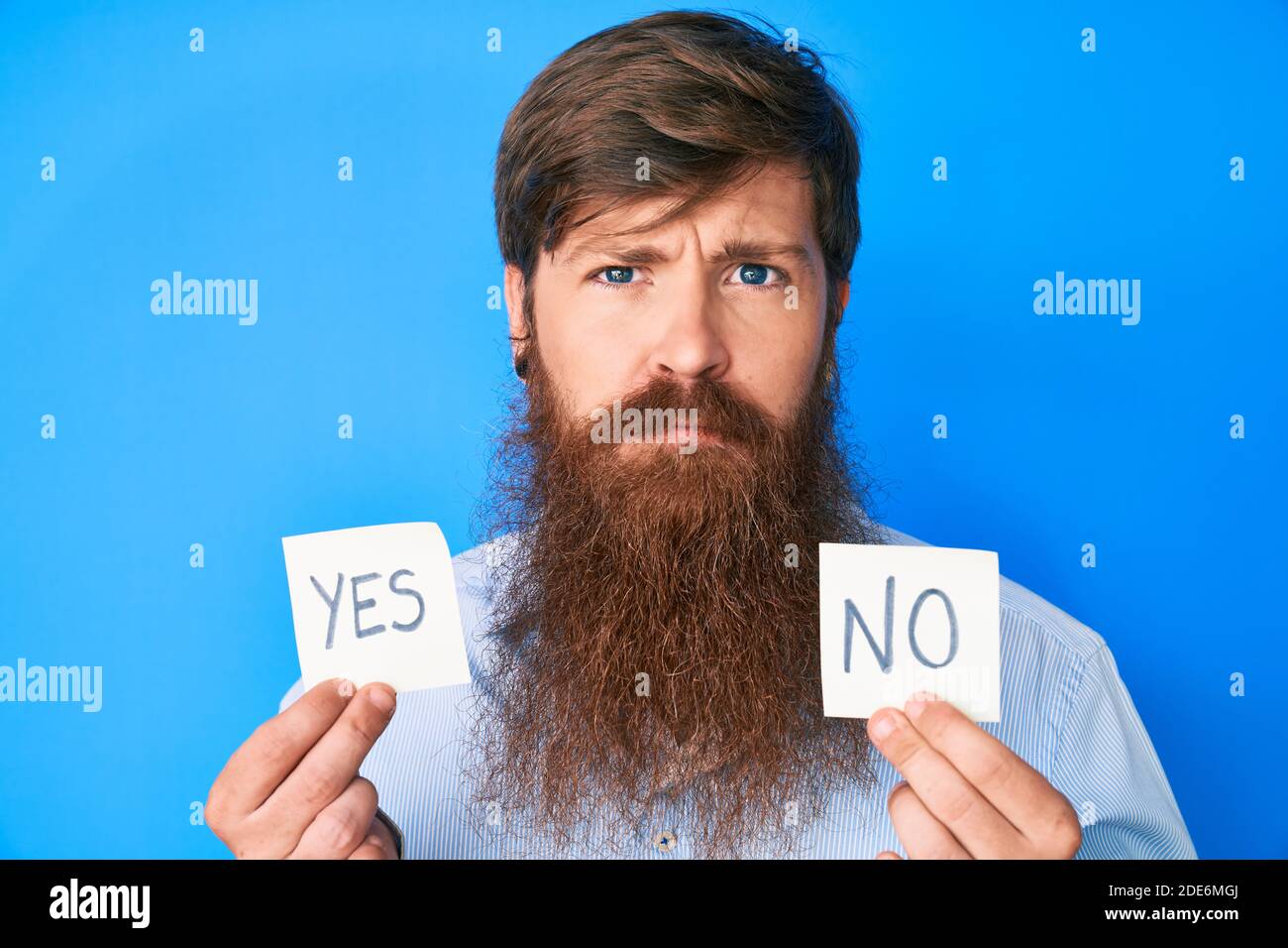 Handsome young red head man with long beard holding yes and no reminder ...